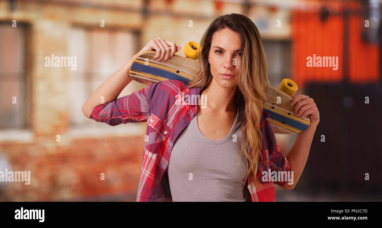 Portrait of white millennial girl posing with skateboard outdoors ...