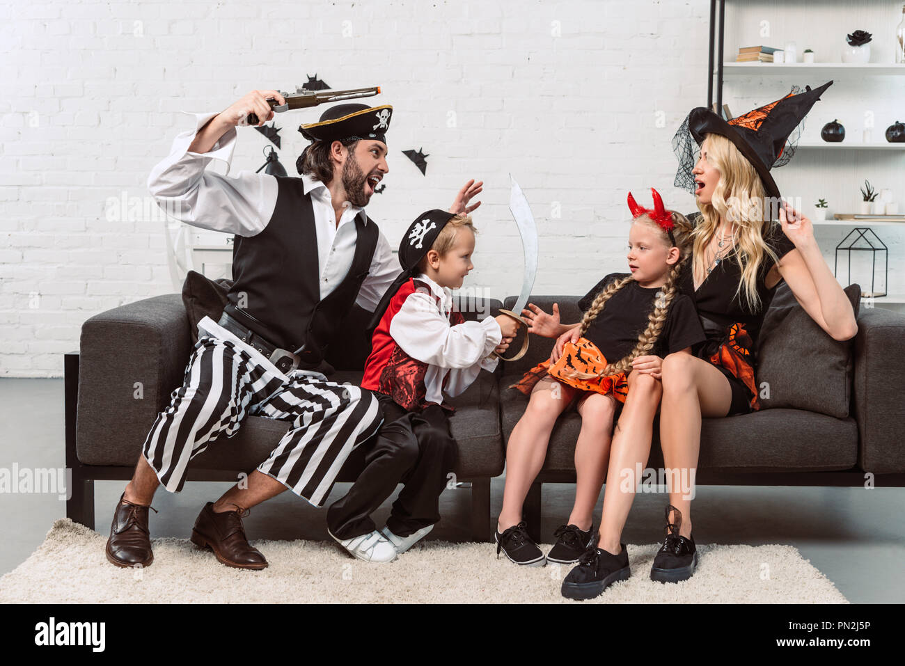 father and son in pirates costumes scaring mother and daughter on sofa ...