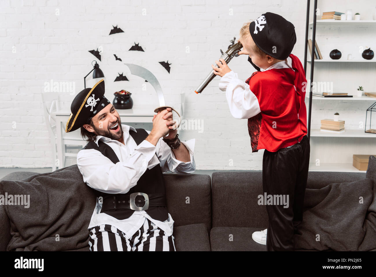 father and son in pirate costumes playing at home, halloween holiday ...