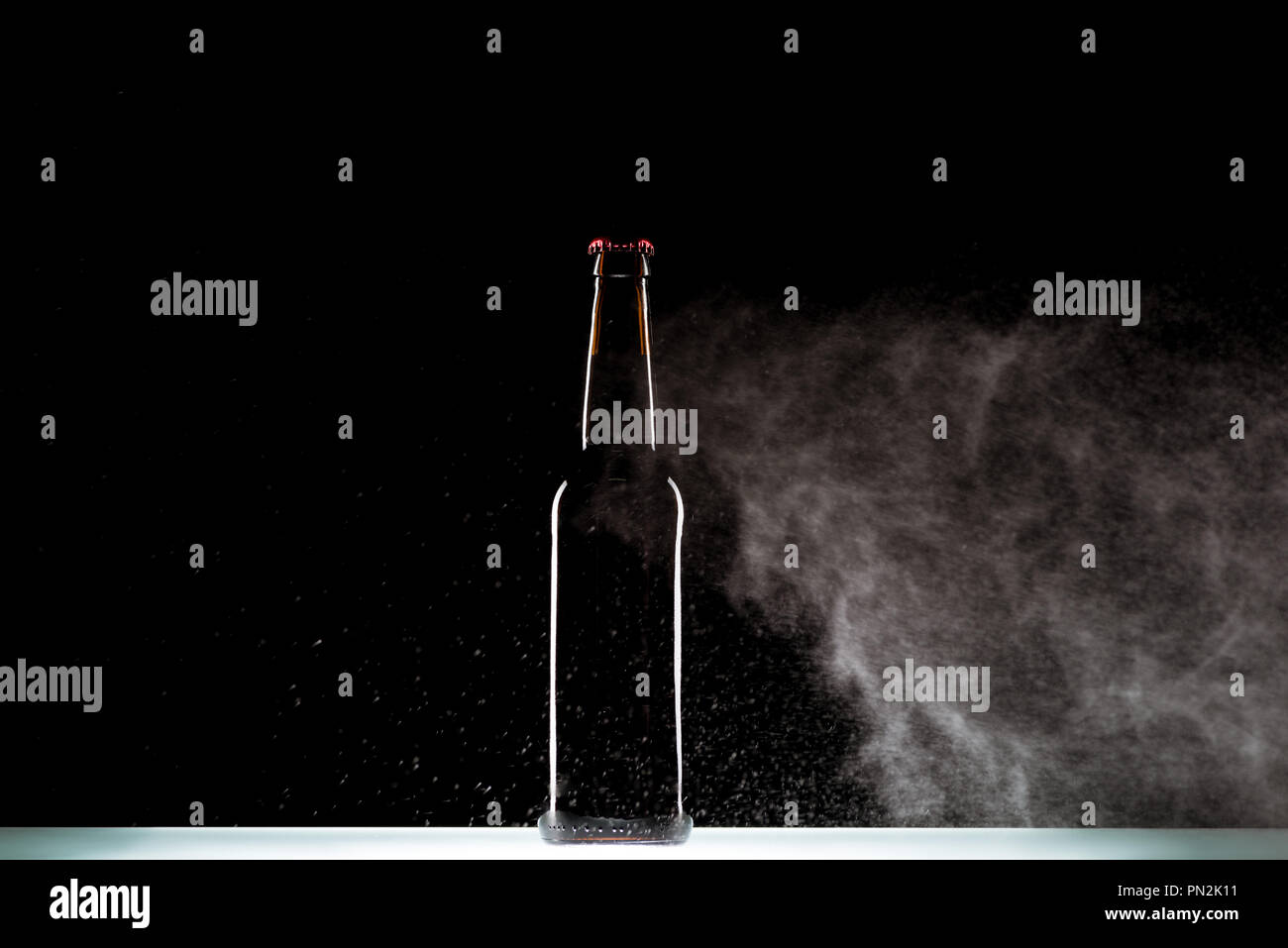 bottle of dark beer with spraying water around at surface on black ...