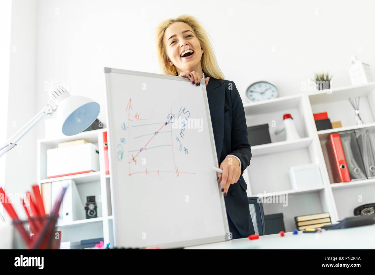A young girl stands near a table in the office and explains the ...