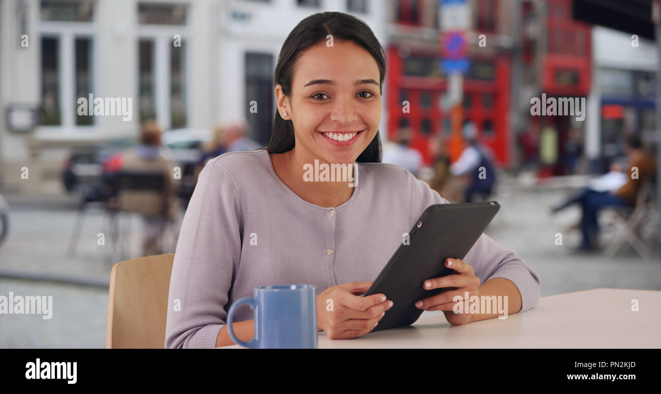 Happy Latina female using her tablet outside at a cafe Stock Photo - Alamy