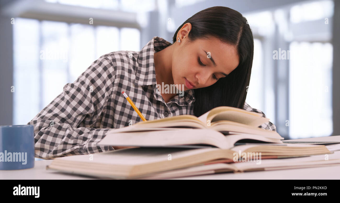 Hispanic female college student studies for an exam at her campus study ...