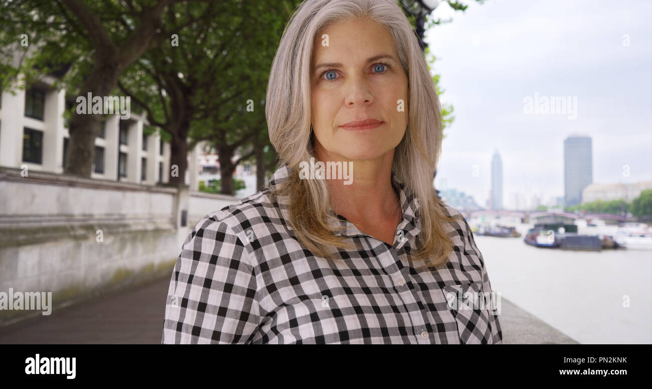Serious white woman stares coldly at the camera on a London street ...