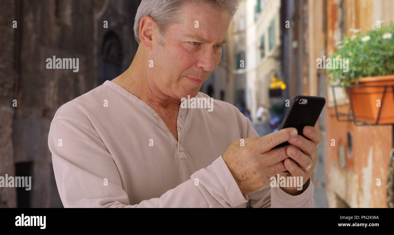 Old white man in street in Italy texts friends on phone Stock Photo - Alamy