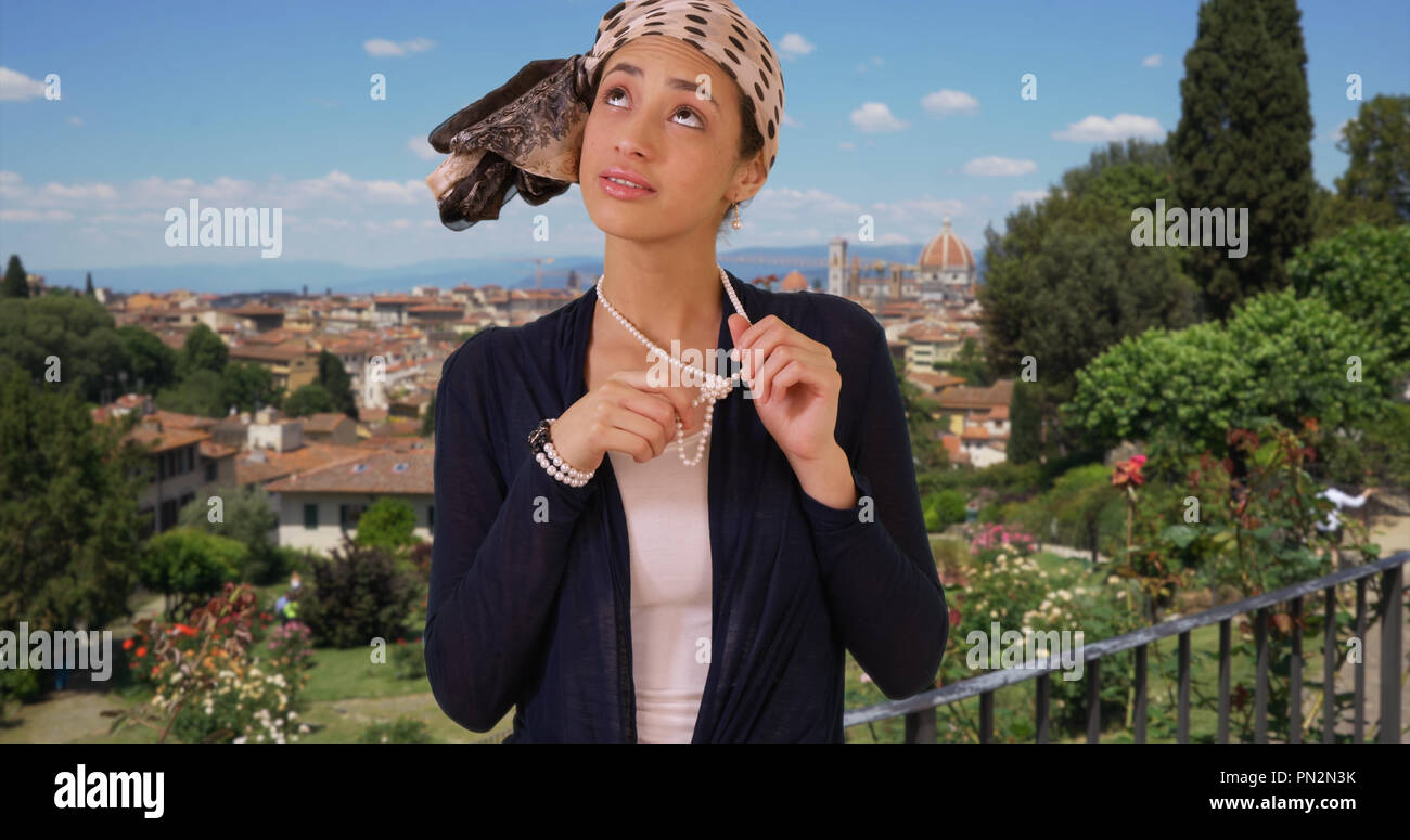 Stylish Latina female plays with pearl necklace outdoors in Florence ...