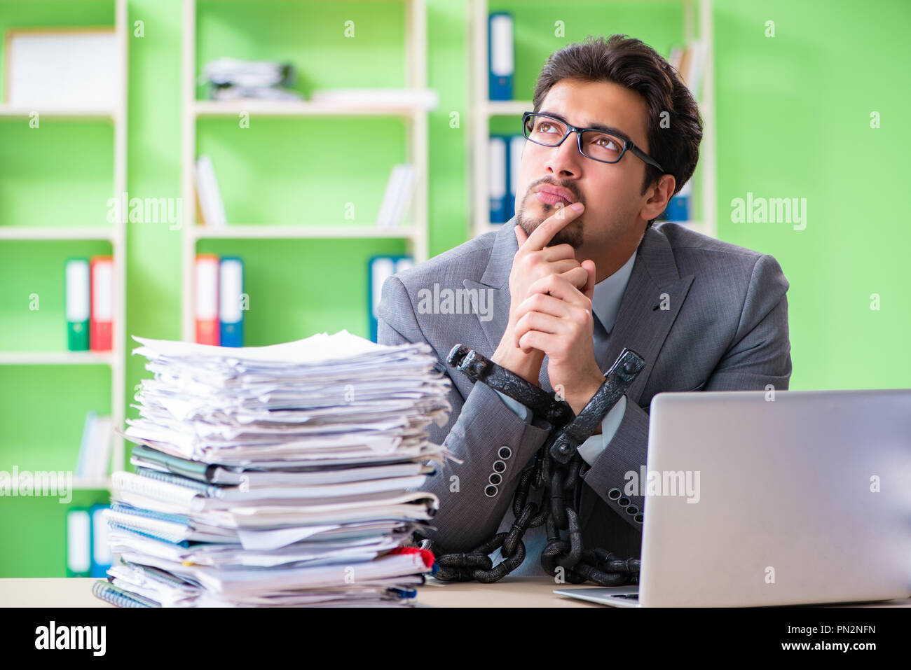 Employee chained to his desk due to workload Stock Photo - Alamy