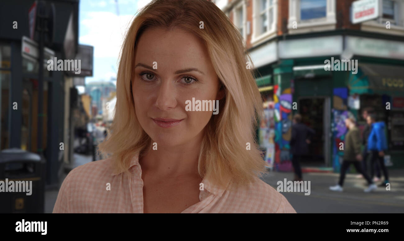 Casual looking Caucasian woman standing outside in city street staring ...