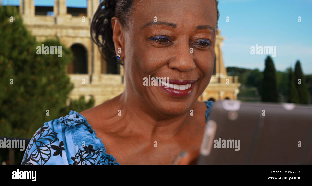 Happy mature black woman using digital tablet near the Coliseum in Rome ...
