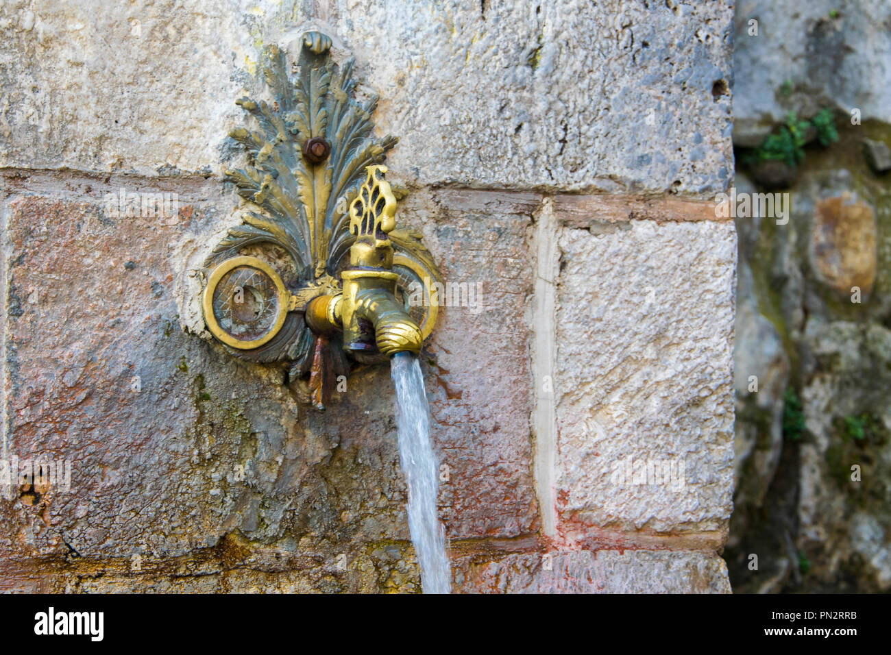 Antique wrought iron tap from which flows water Stock Photo - Alamy
