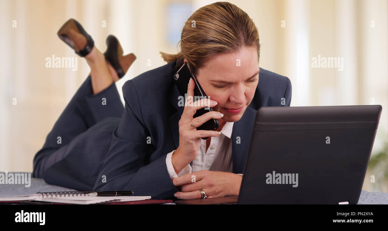 Businesswoman lying on stomach in bedroom answering phone call Stock ...