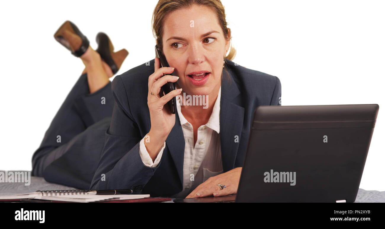 Businesswoman lying on stomach answering phone call and working on ...