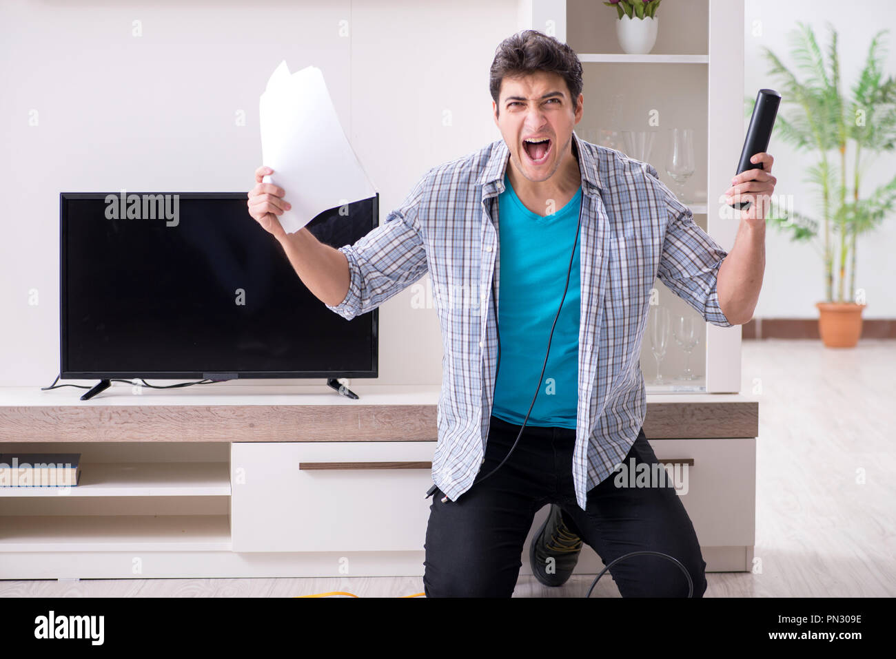 Man trying to fix broken tv Stock Photo - Alamy