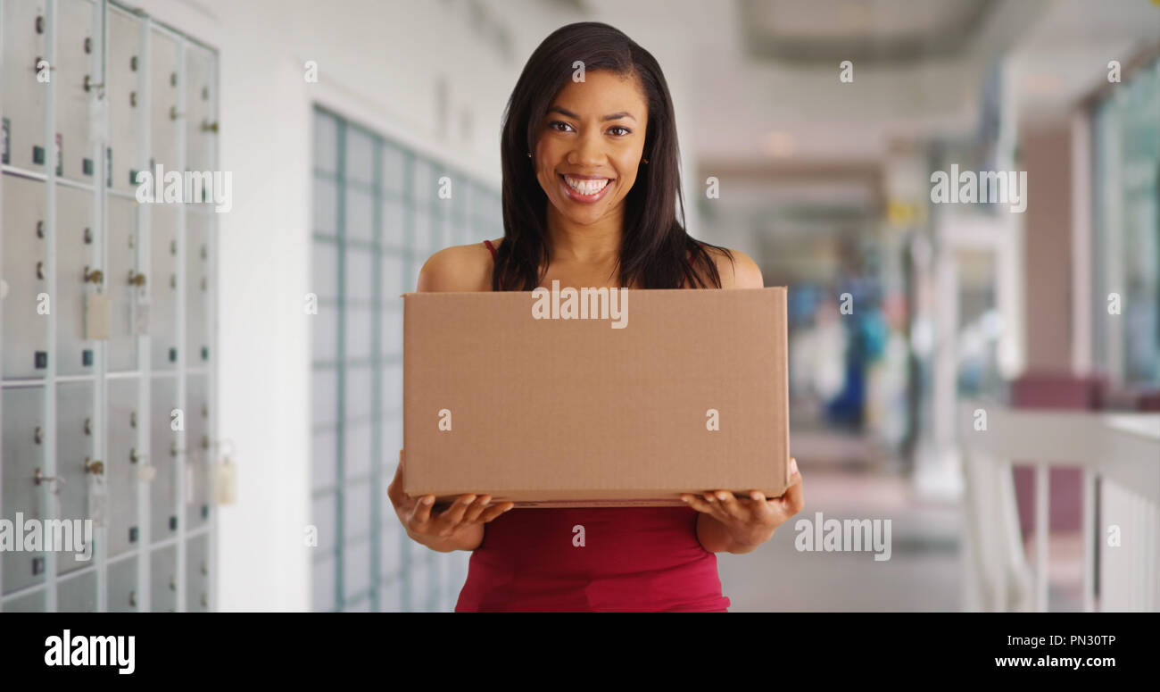 Portrait of pretty African American female at post office carrying ...