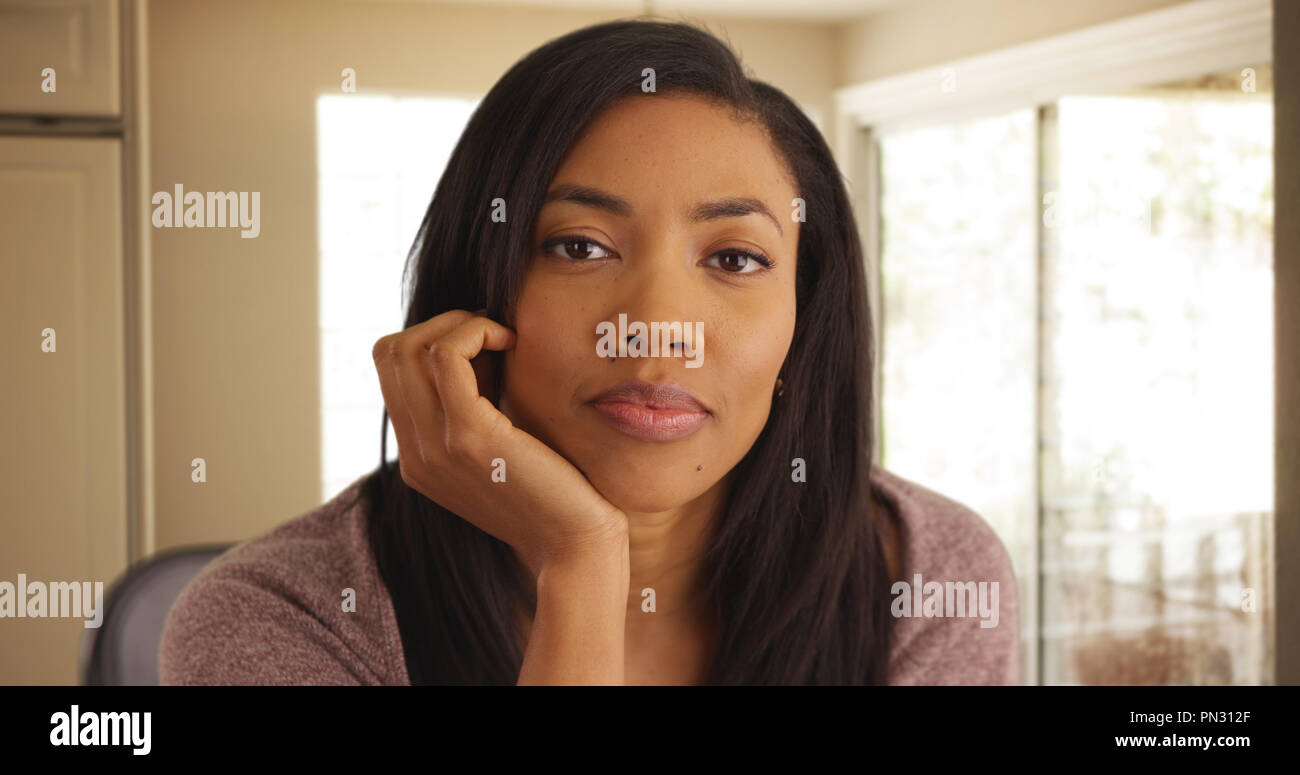 Portrait of lovely black female resting hand under chin looking at ...