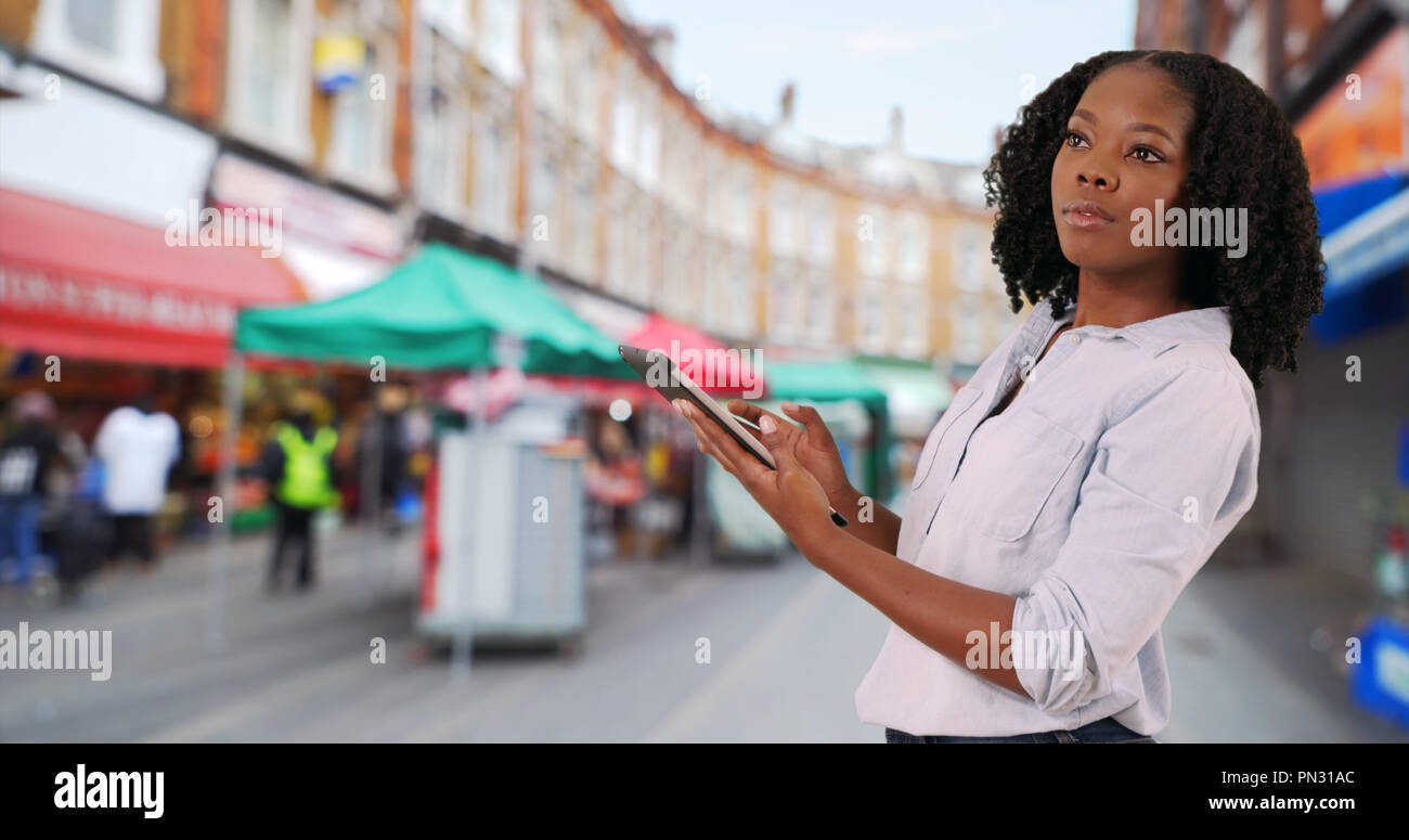 Attractive businesswoman at popular Brixton street market using tablet ...