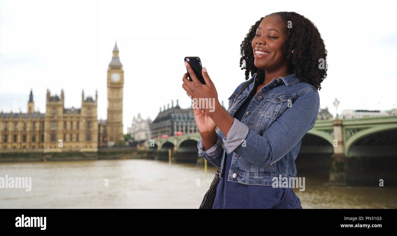 Cute black woman traveling in London laughs at funny text from ...
