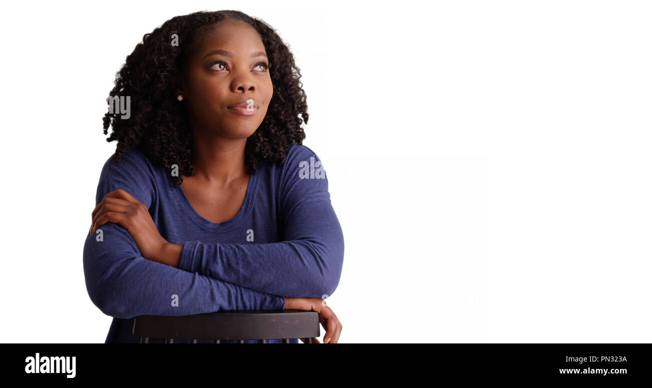 Portrait of black woman sitting backwards in chair on white background ...