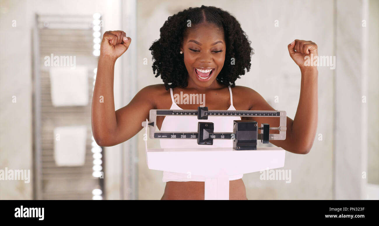 Beautiful black woman happily weighs herself on scale in bathroom Stock ...