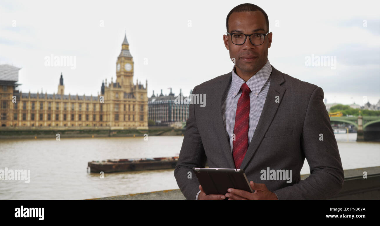 Aspiring black businessman holding tablet device near Big Ben in London ...