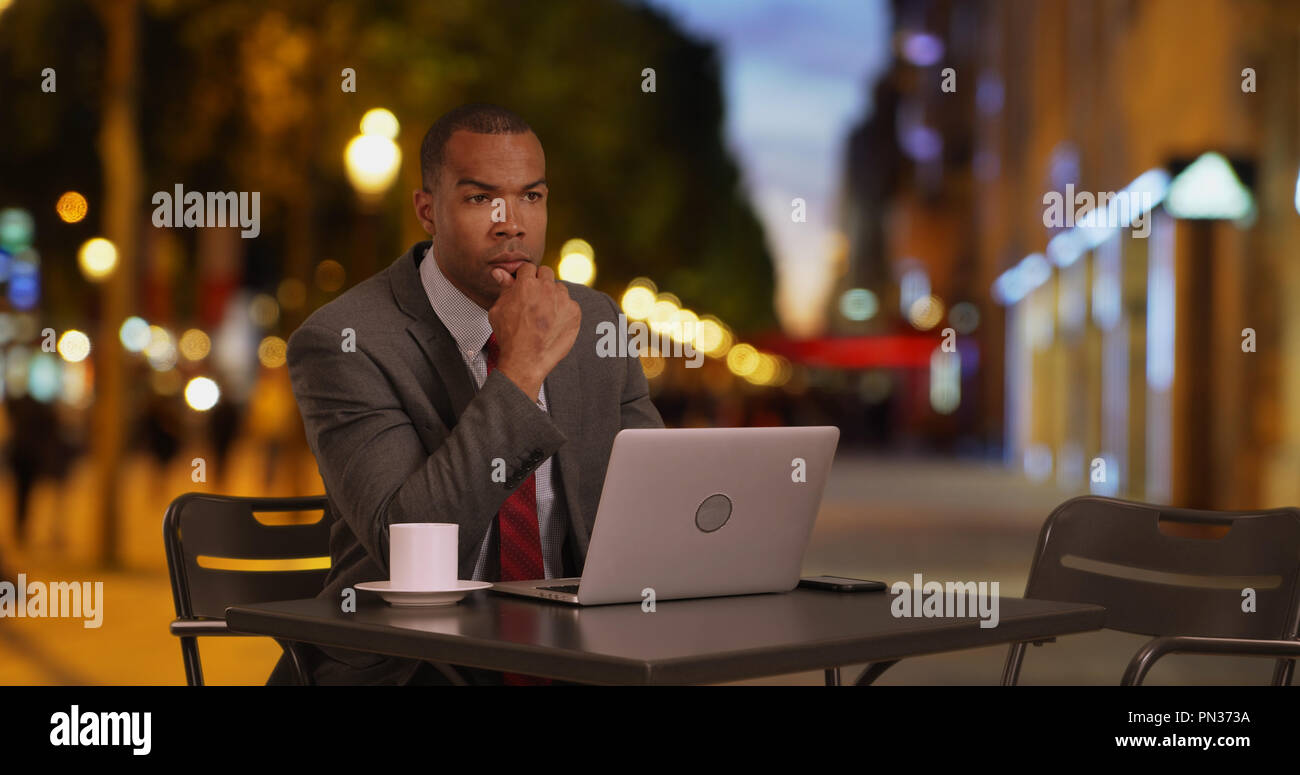 African-American professional finishing up work on computer at cafe in ...