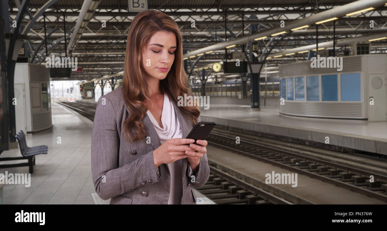 Well-dressed white female sending message on mobile device at train ...