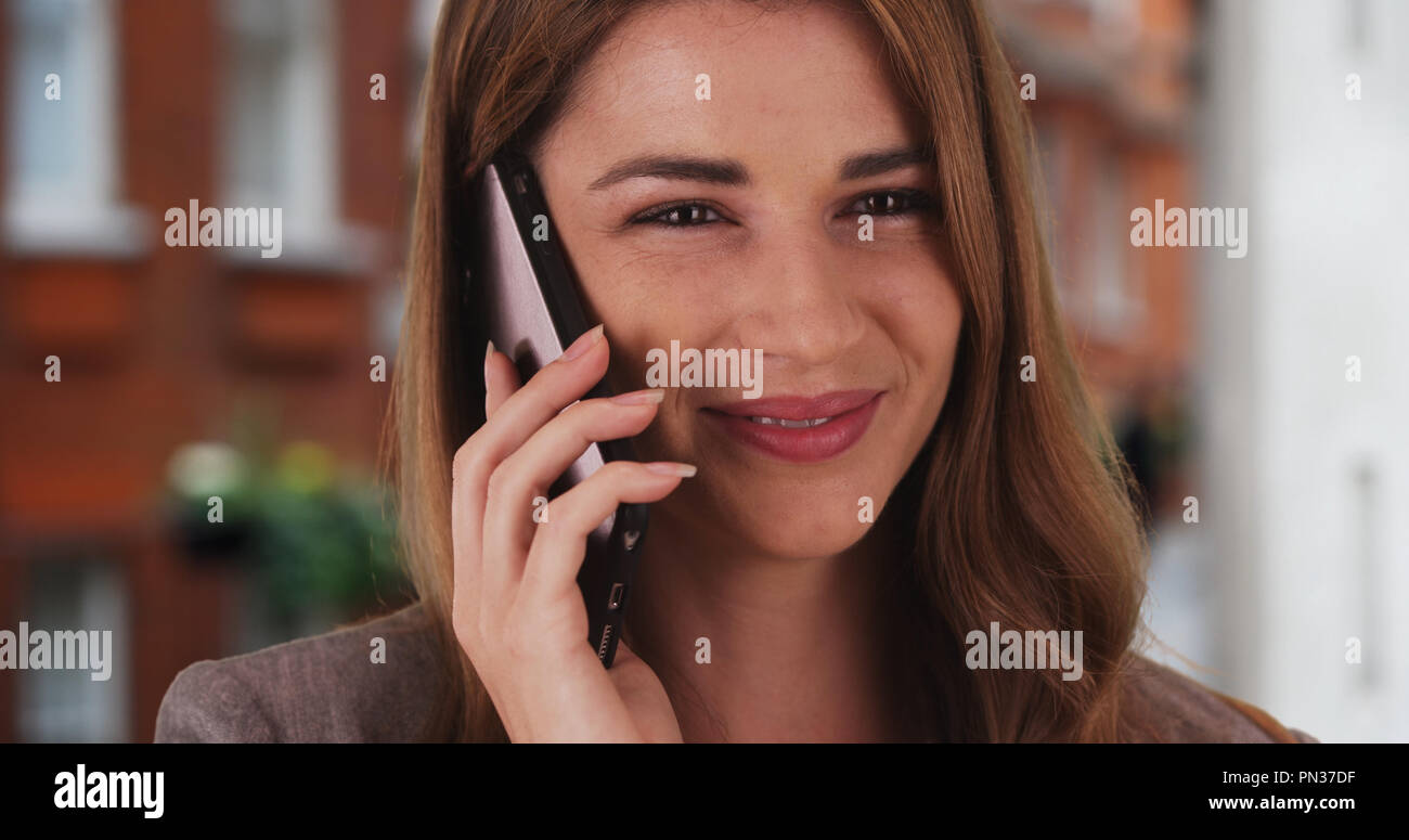 White professional woman talking with client on smartphone outside ...