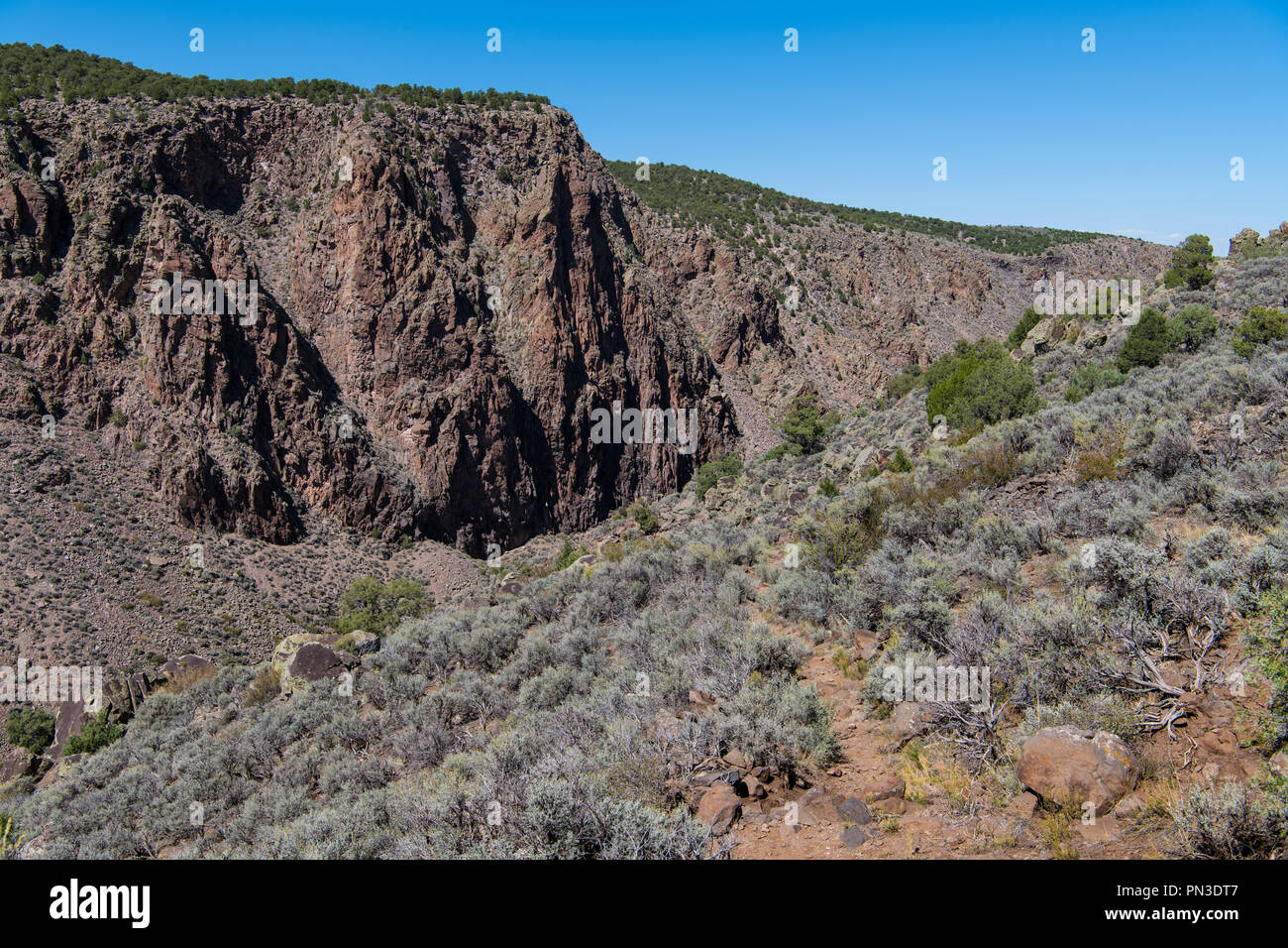 Narrow hiking trail leading through a rugged landscape towards a rocky ...
