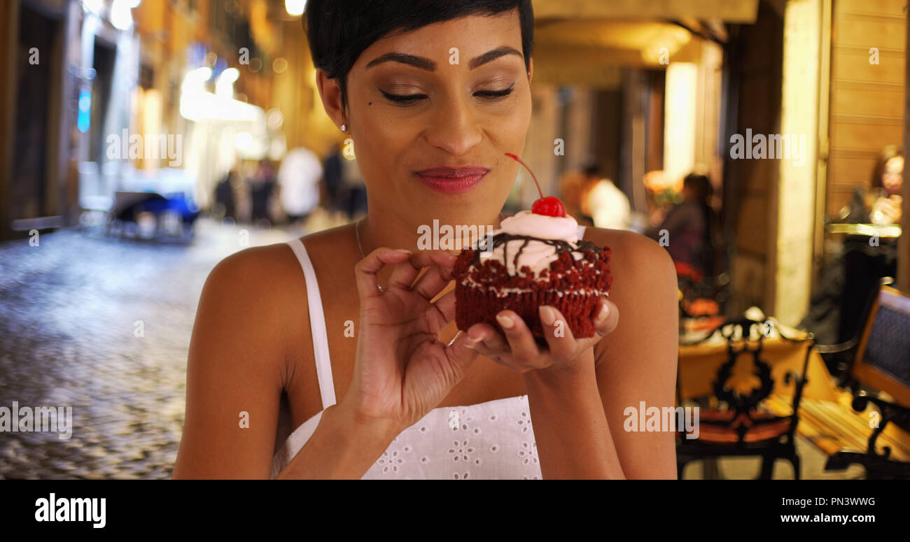 Black woman takes messy bite of huge red velvet cupcake Stock Photo - Alamy