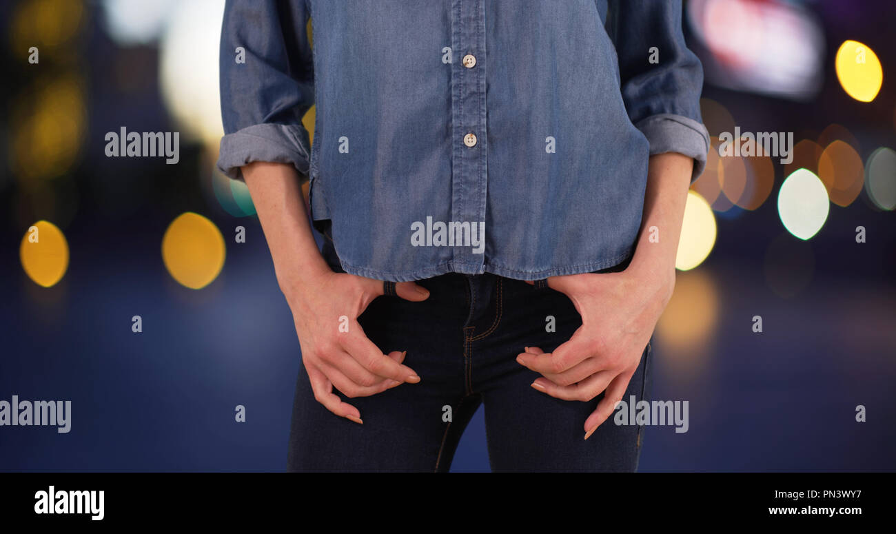 Close up of woman hooking thumbs into the belt loop of jeans on urban ...
