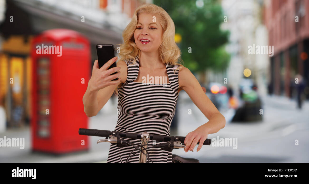 Pretty cyclist in London England checks mobile phone for directions ...