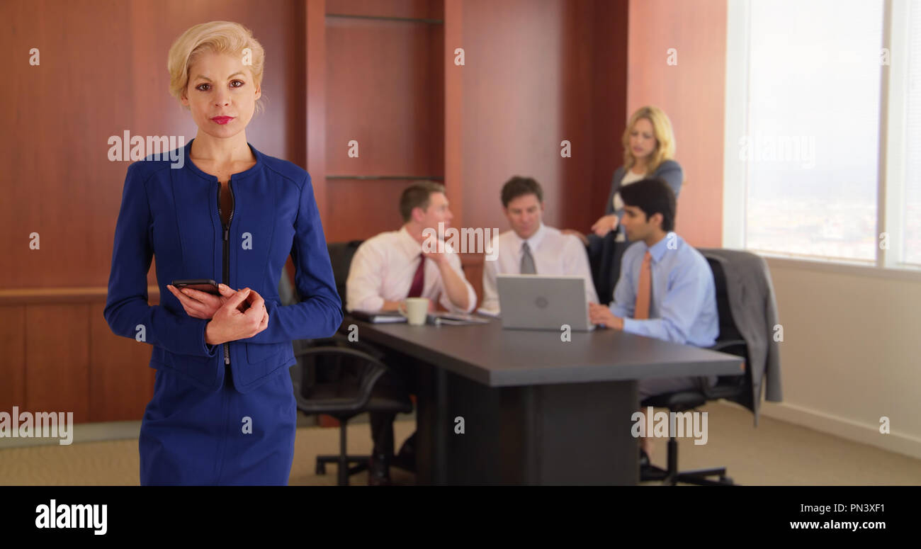 Female executive looking at camera employees brainstorming in ...