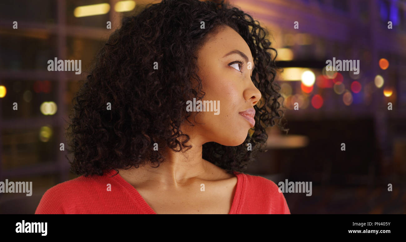 African young lady thinking to herself in urban setting in the evening ...