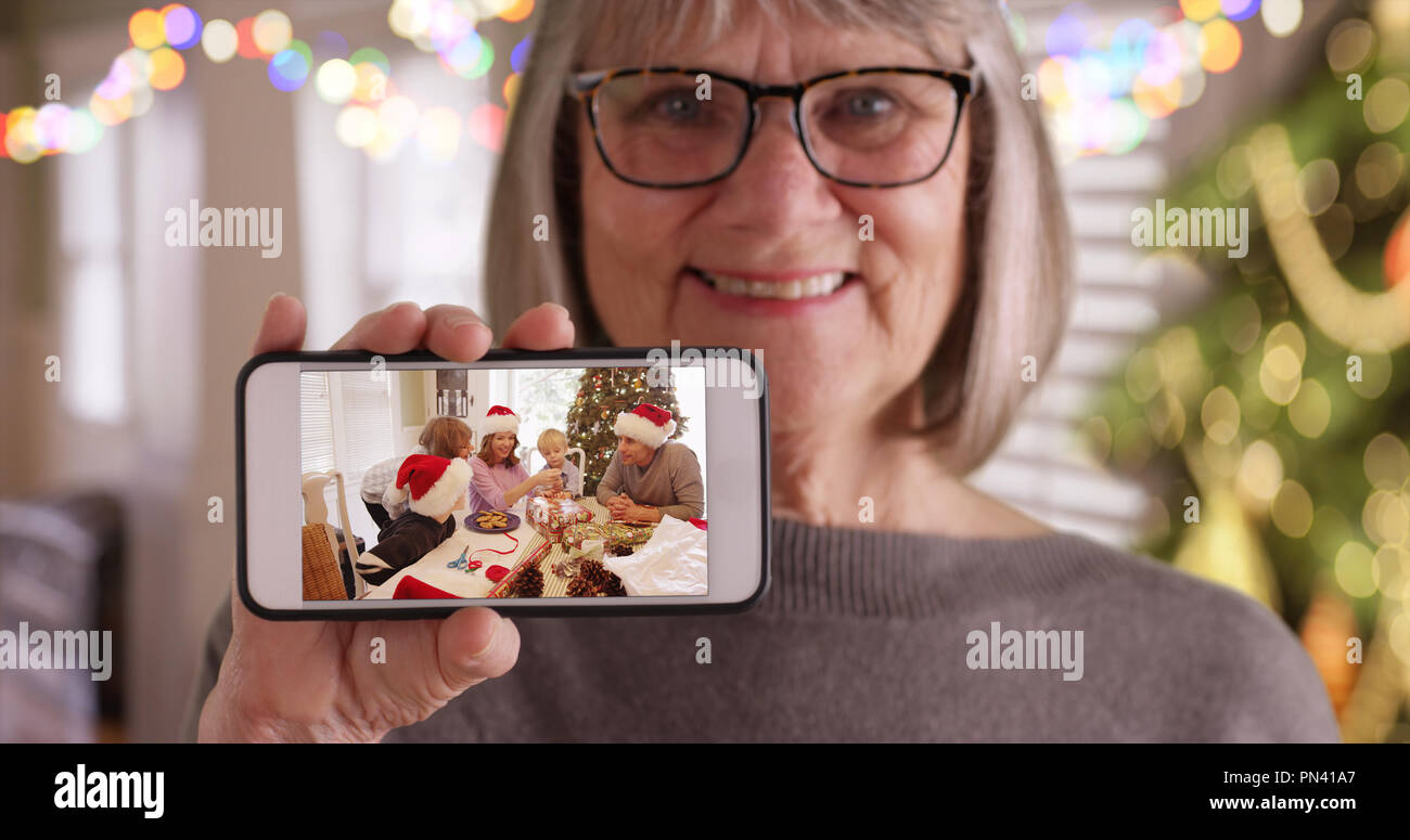 Happy grandma showing smartphone video of her with family on Christmas ...