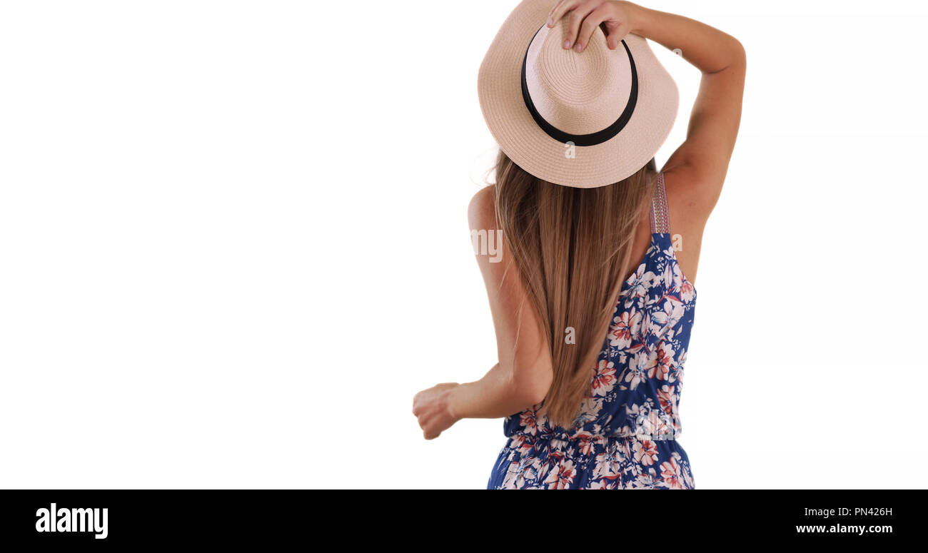 Rear shot of woman holding hat while feeling wind on white background ...