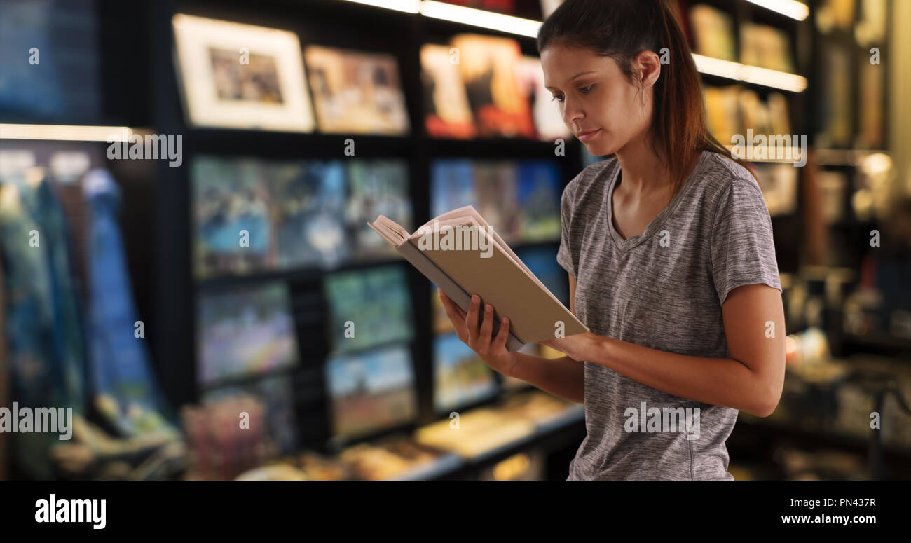 Beautiful young woman reading in bookstore Stock Photo - Alamy