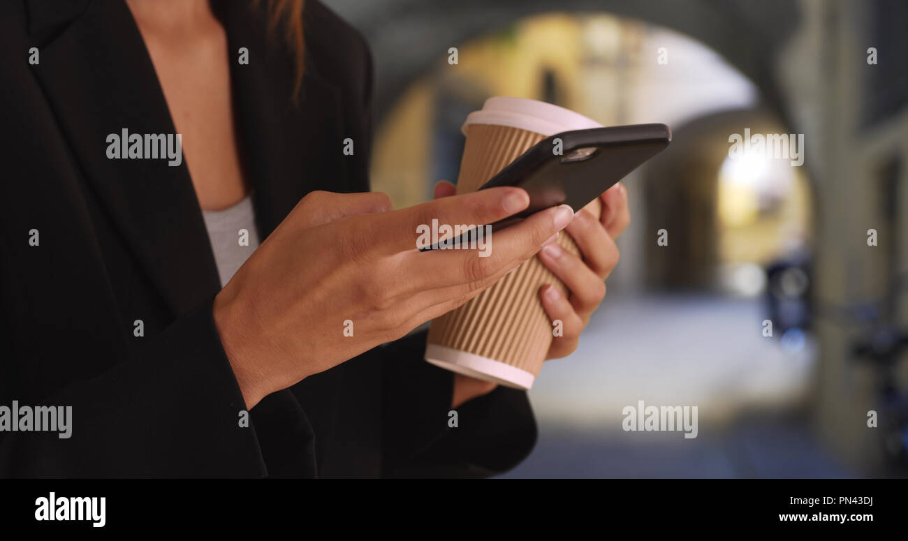 Close up shot of female hands texting on smartphone and drinking coffee ...