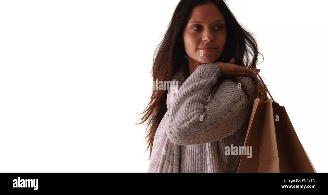 Millennial woman looking around while carrying shopping bags on white ...