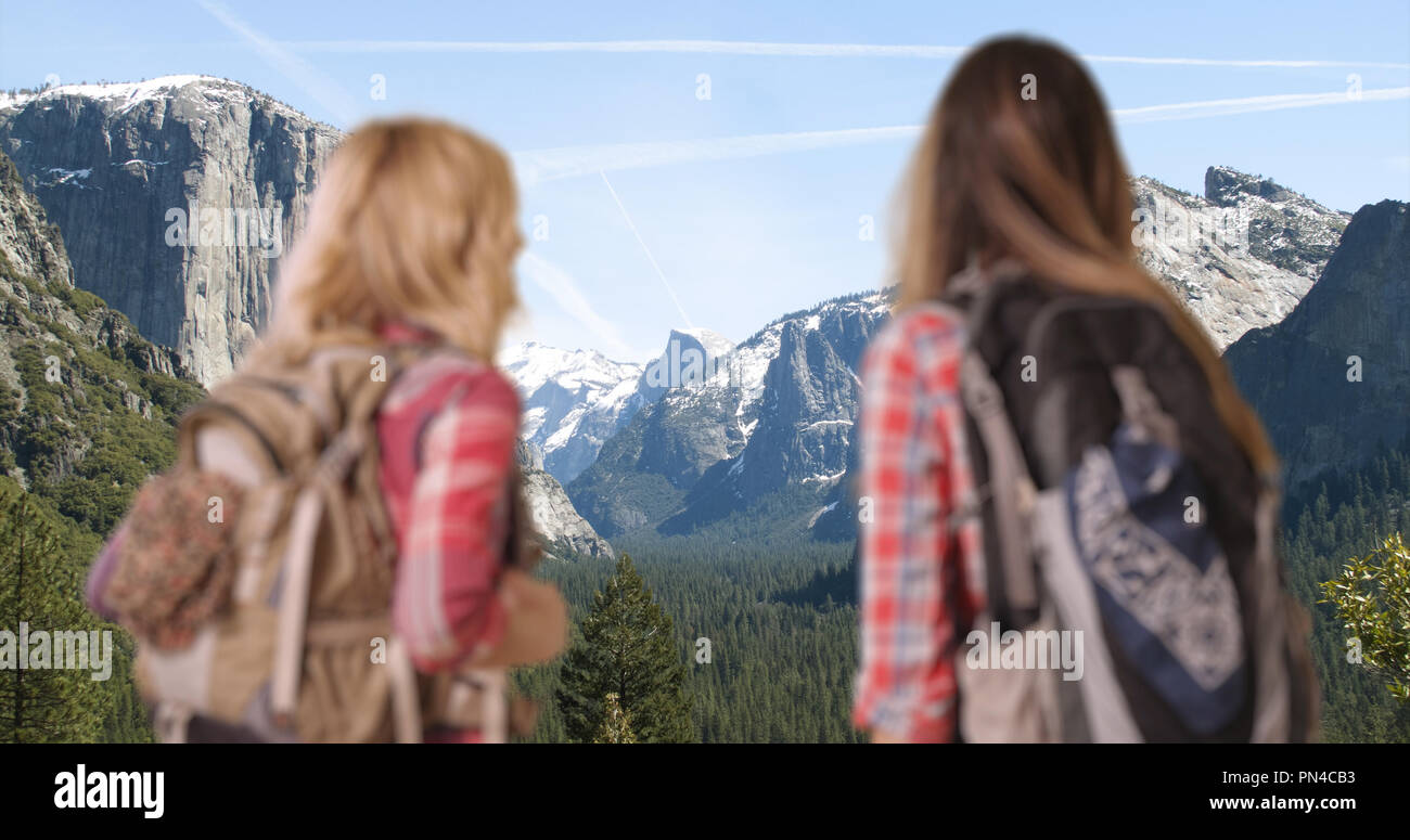 Couple of young female hikers out in nature setting enjoying view of ...