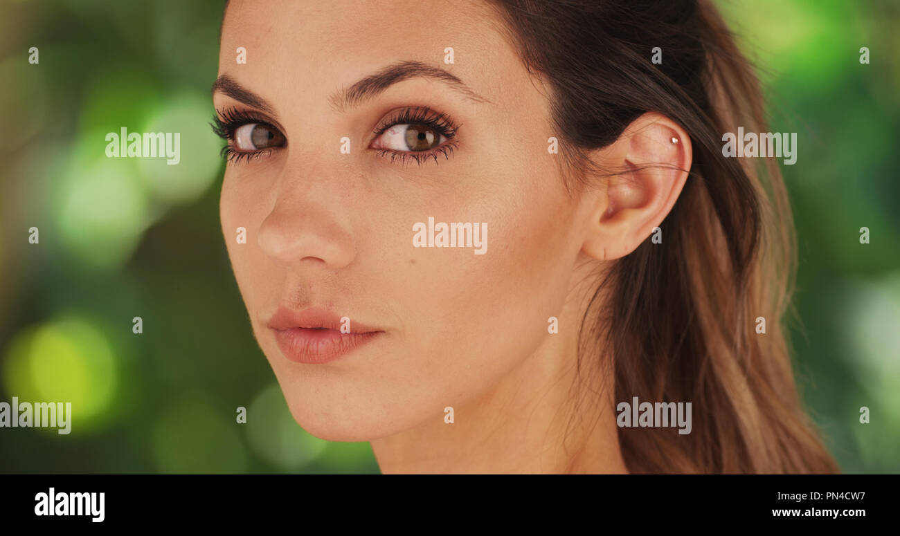 Close-up profile of beautiful model turning head to camera on green ...