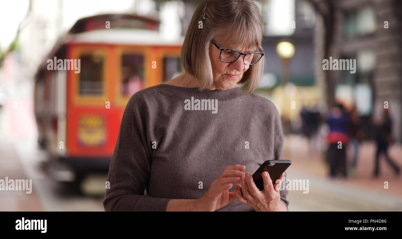 Somber Caucasian lady reading distressing e-mail on phone near trolley ...