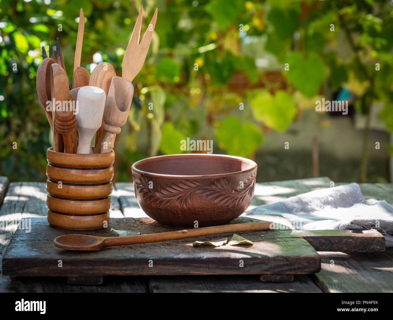 empty clay plate and various wooden kitchen objects in a container on a ...