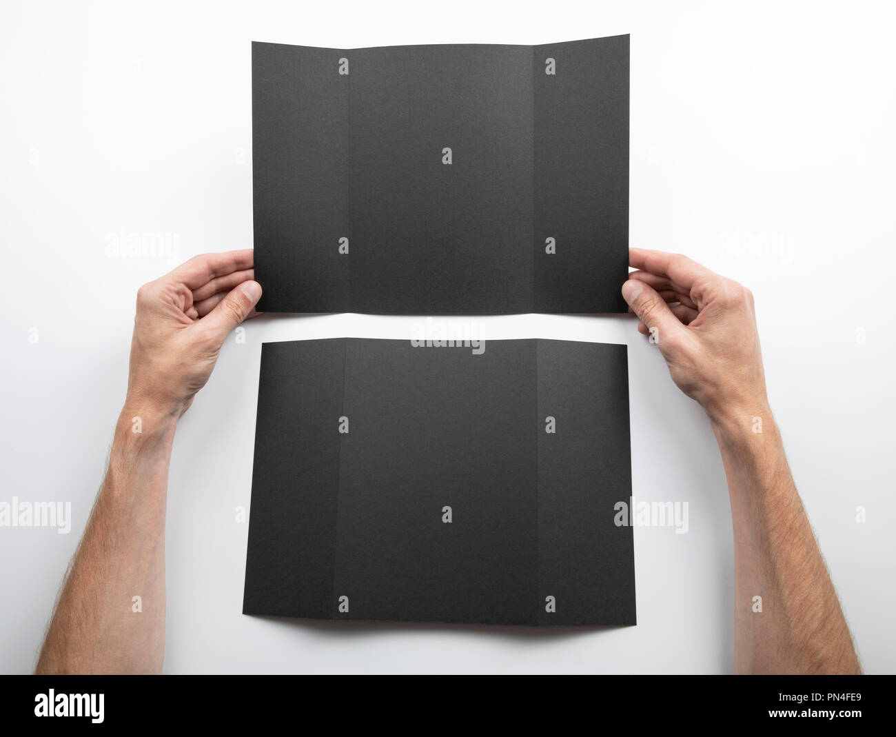Mens hands holding empty black booklet on white background. View from ...