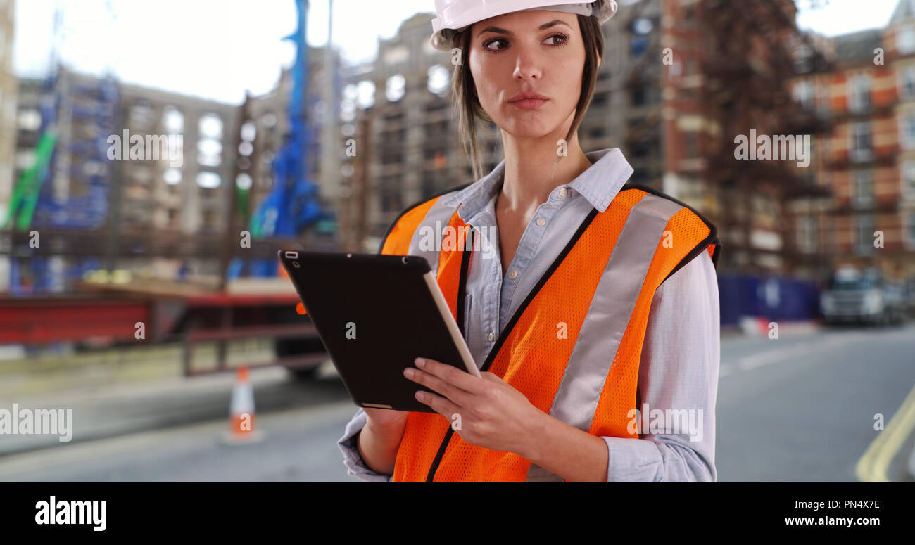 Focused female construction worker at work on pad device at ...