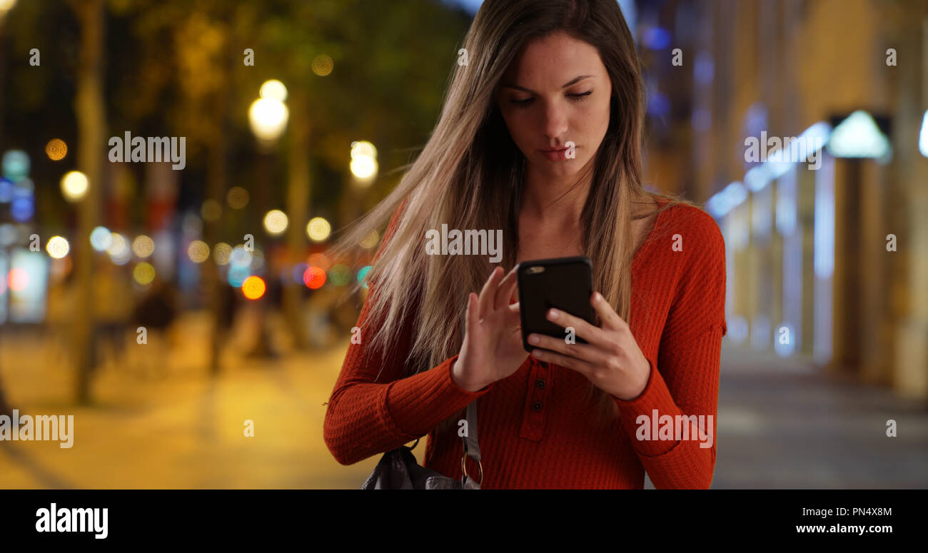Young lady pulling smartphone out of bag to reply to text on Champs ...