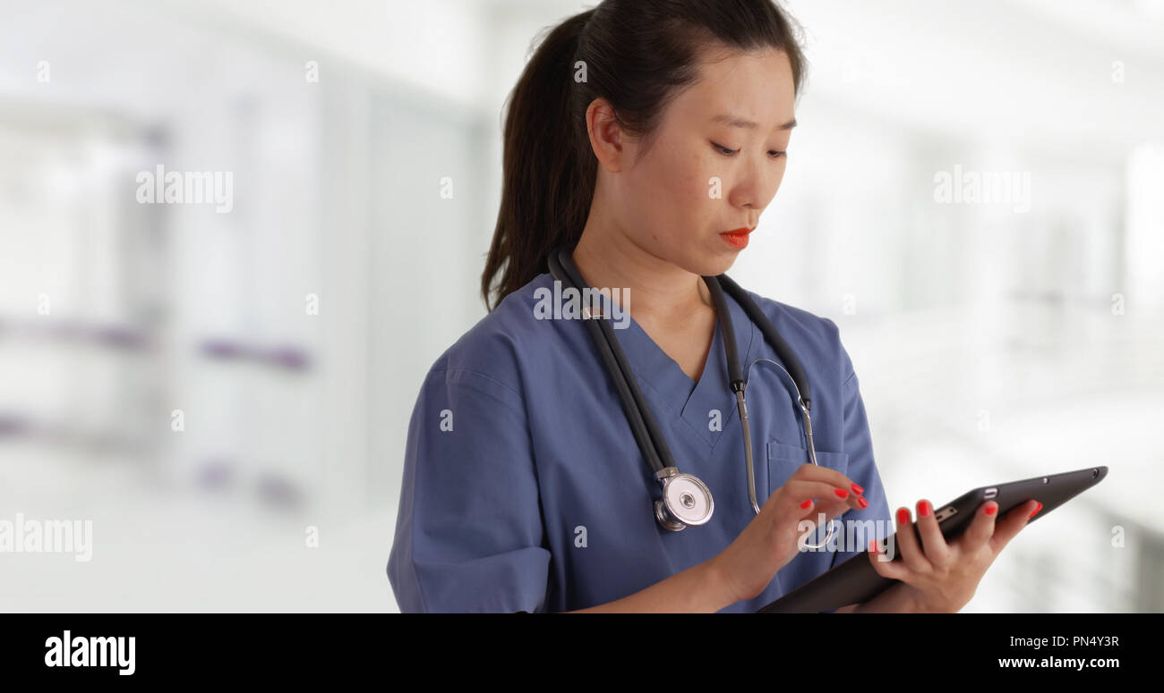 Professional young medical nurse or doctor using portable tablet inside ...