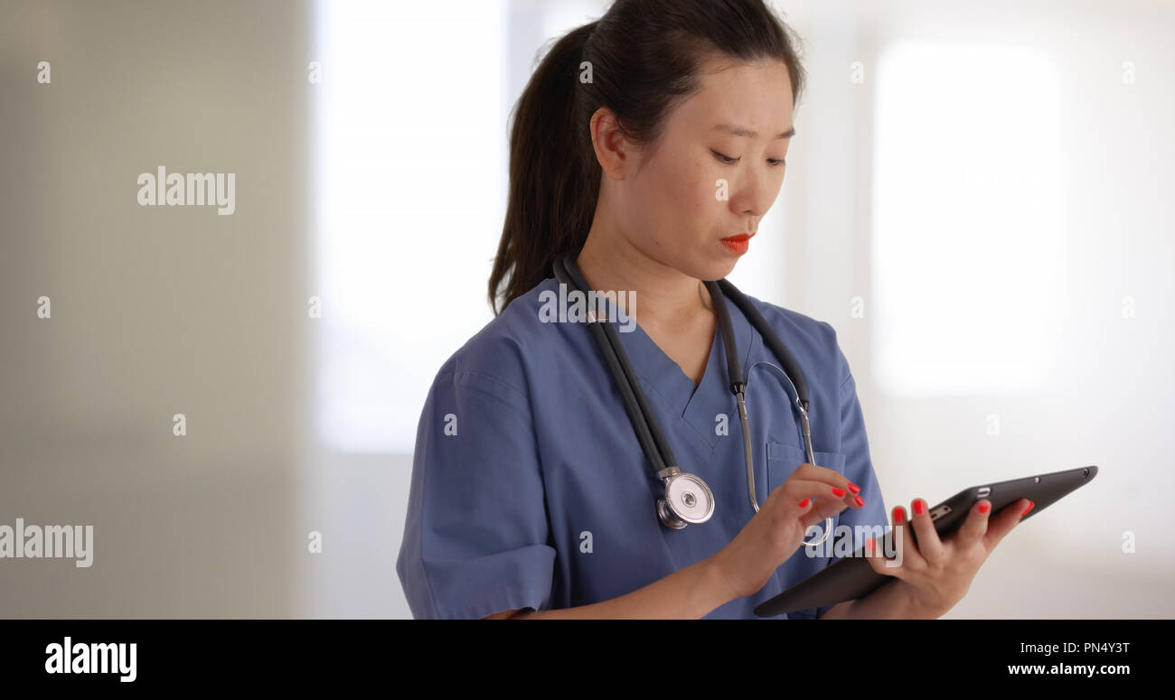 Professional young doctor or nurse using portable tablet inside ...