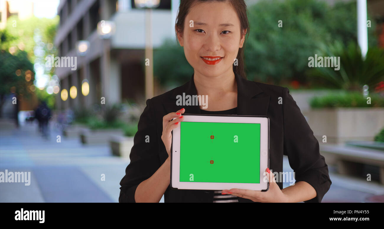 Smiling business lady holding handheld tablet with green screen in ...