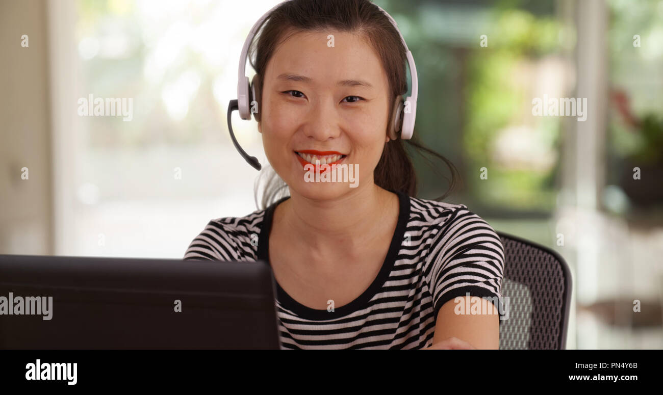Technical support agent with headset smiling at camera working from ...