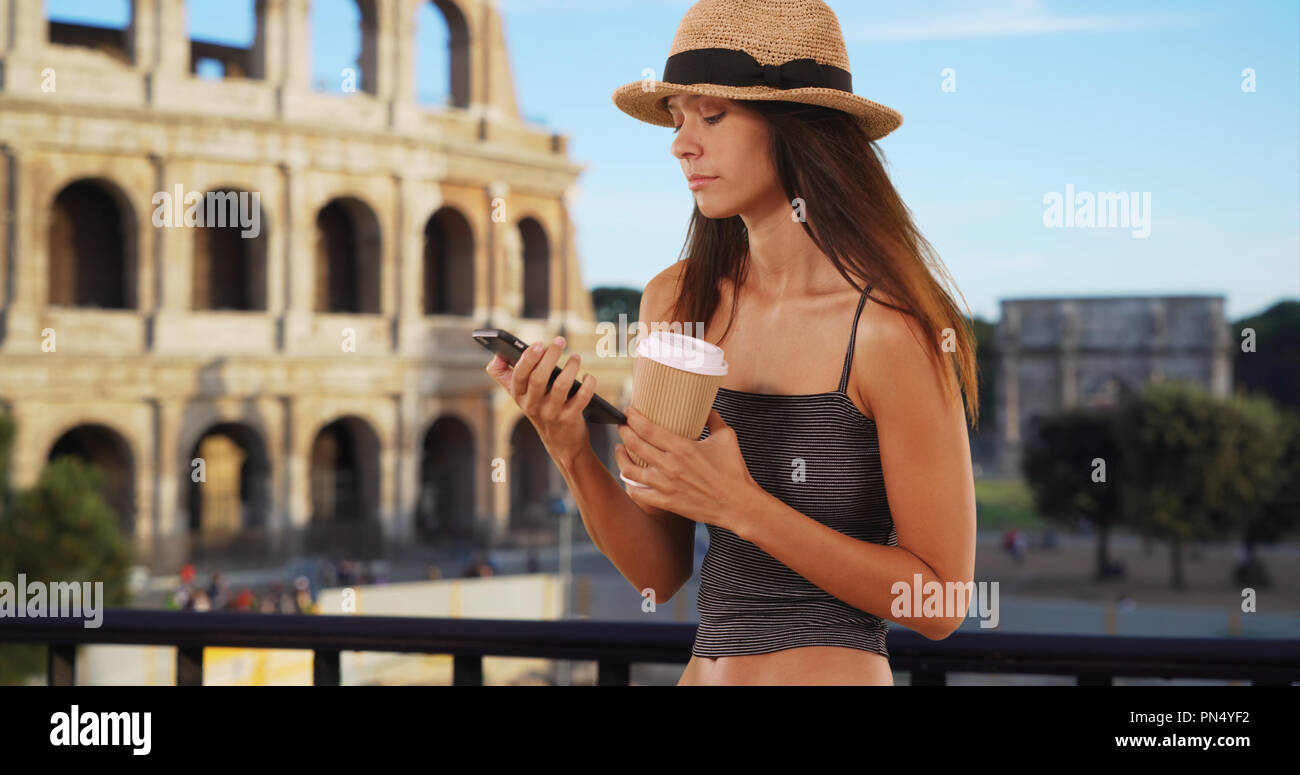 Tourist woman near the Roman Coliseum texting with cellphone wearing ...